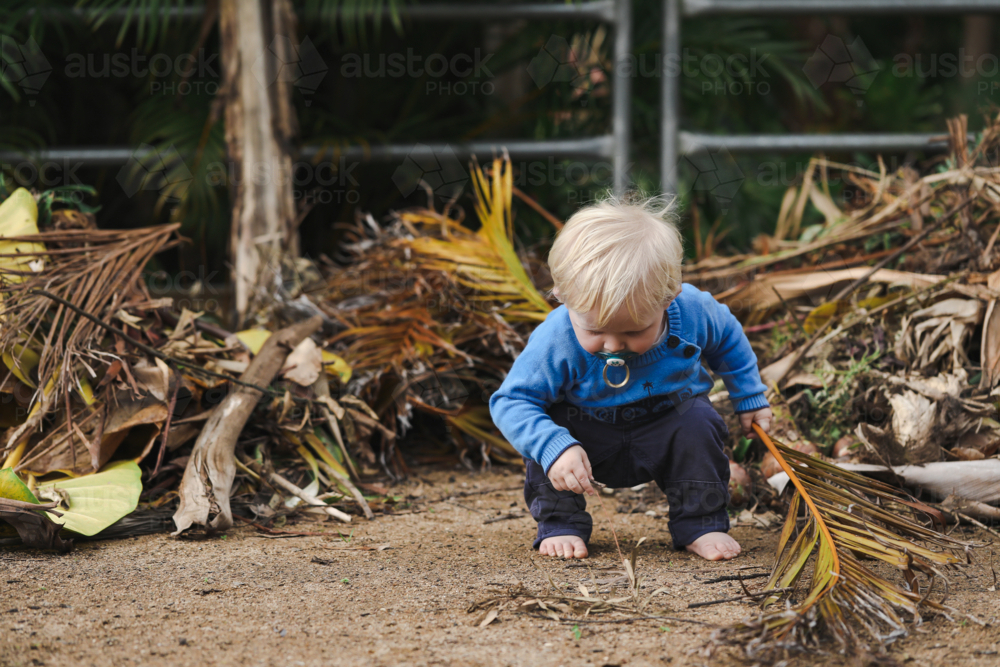 Image of Toddler boy with dummy and bare feet playing in the dirt ...