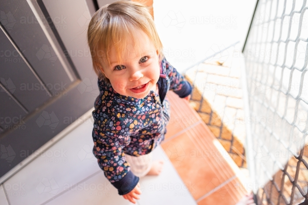Image of Toddler girl by front door step of house waiting to go outside ...