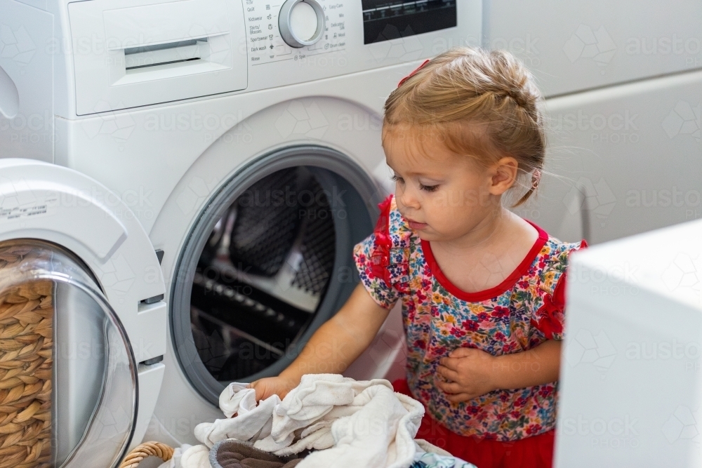 Image of Toddler girl helping get the washing out of the machine ...
