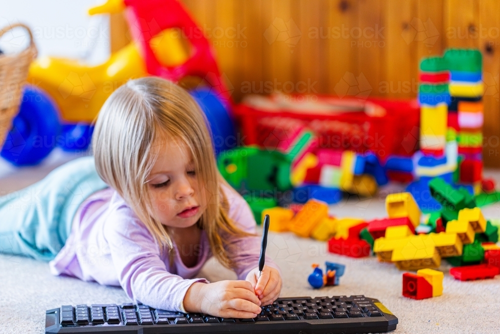 Image of Toddler girl using tool to pull apart keyboard surrounded by ...