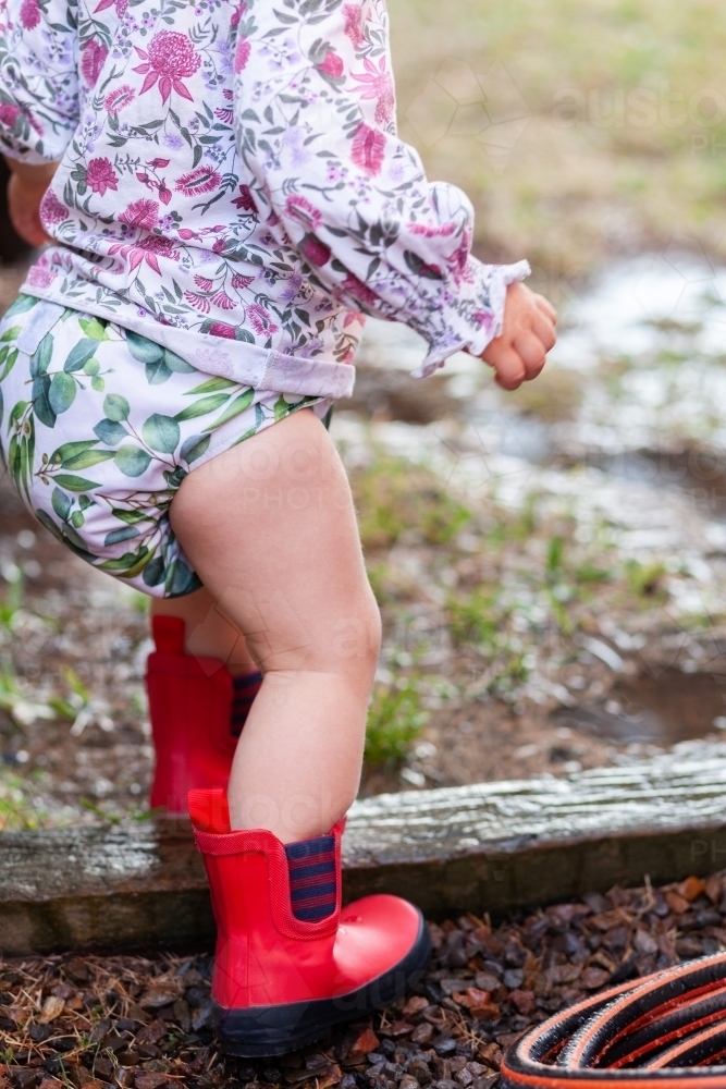 Image of toddler in gumboots stomping in puddles in backyard - Austockphoto