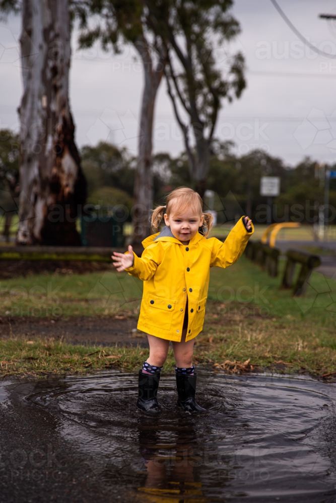 Image of toddler stomping in a puddle while wearing a bright yellow ...