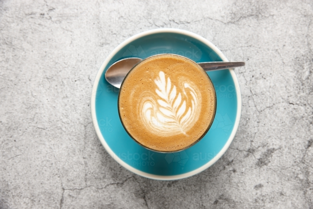 Image of Top-down view of latte on blue saucer with teaspoon - Austockphoto