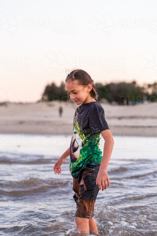 Image of Torres Strait Island boy wading in ocean water at dusk ...