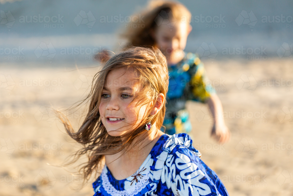 Image of Torres Strait Islander girl at beach on windy day wearing traditional floral dress ...