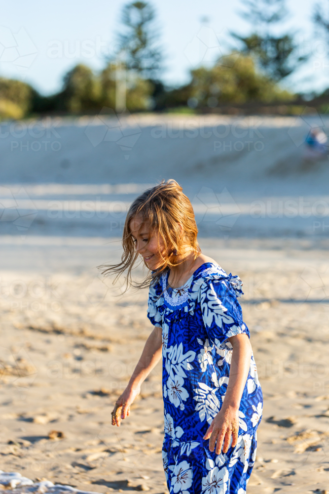 Image of Torres Strait Islander girl at beach on windy day wearing traditional floral dress ...