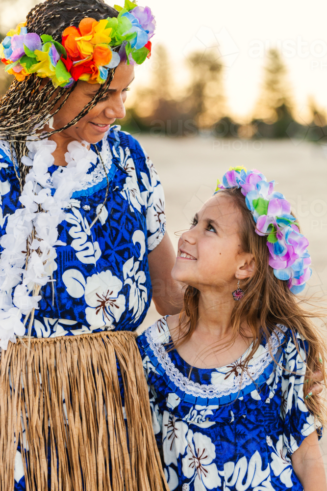 Image of Torres Strait Islander girl looking at mother in traditional dancer floral dress skirt ...