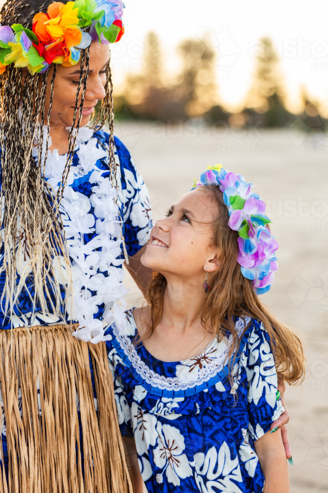 Image of Torres Strait Islander girl looking up at mother in traditional dancer floral dress and ...