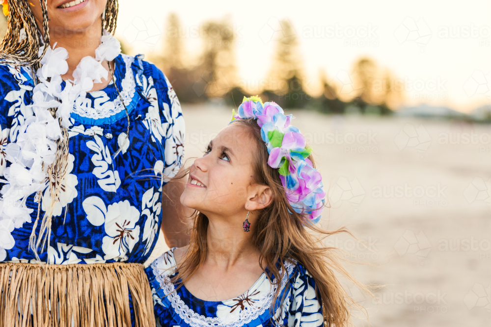Image of Torres Strait Islander girl looking up at mother in traditional dancer floral garland ...