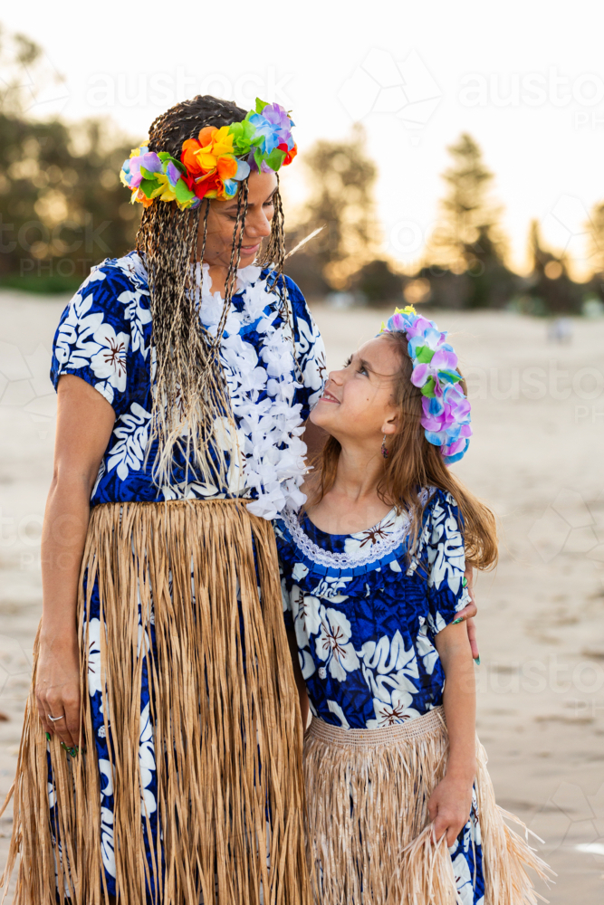 Image of Torres Strait Islander girl looking up at mother in traditional dancer grass skirt and ...