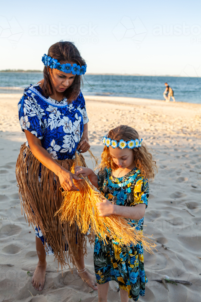 Image of Torres Strait Islander mother getting daughter dressed in skirt for cultural ...
