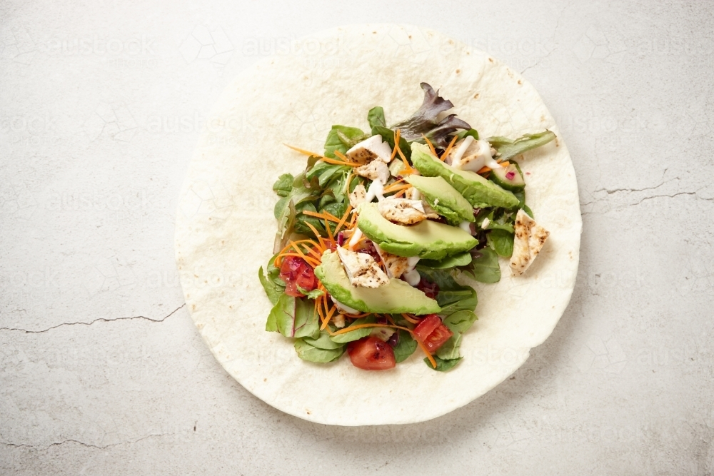 Image of Tortilla wrap topped with spinach, avocado, tomato, chicken ...