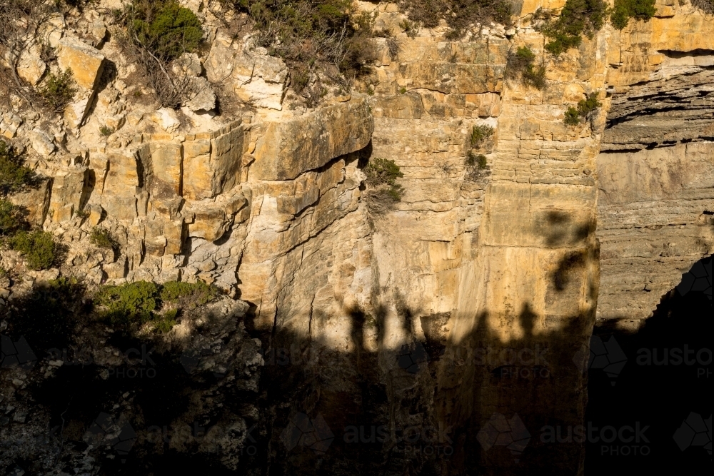 Image of tourists making shadows on a cliff face - Austockphoto