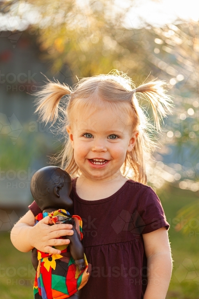 Image of Toy Aboriginal Australian doll in colourful dress held by ...