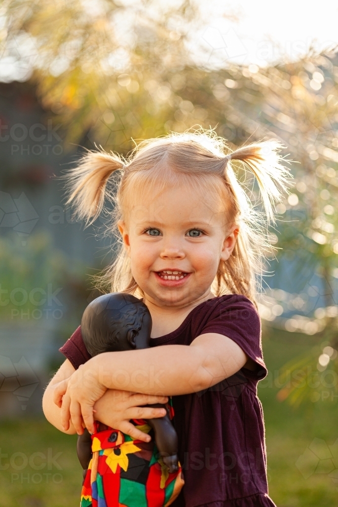 Image of Toy Aboriginal Australian doll in colourful dress held by ...