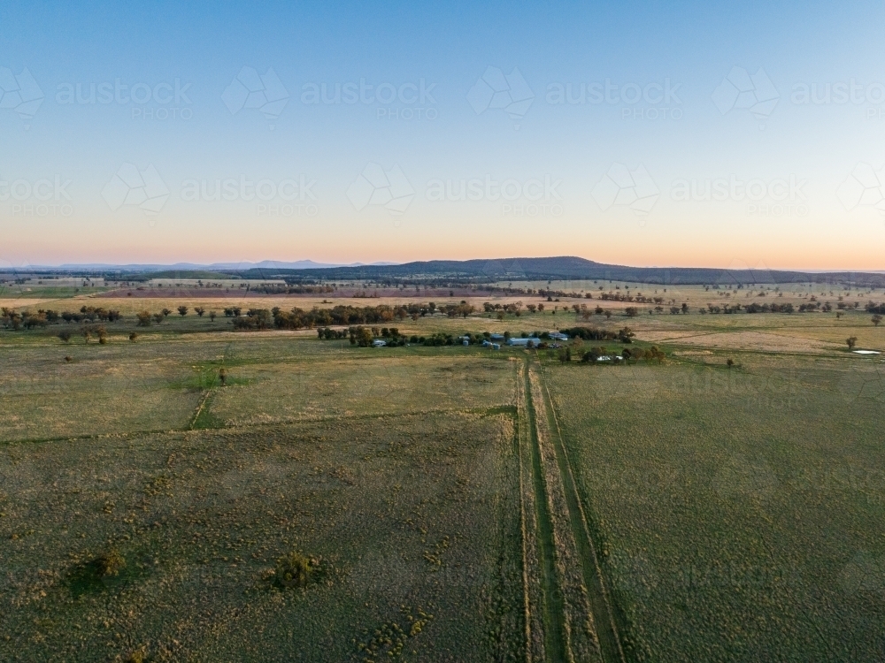 Image of Track through pastoral farm paddock at sunset seen from drone ...