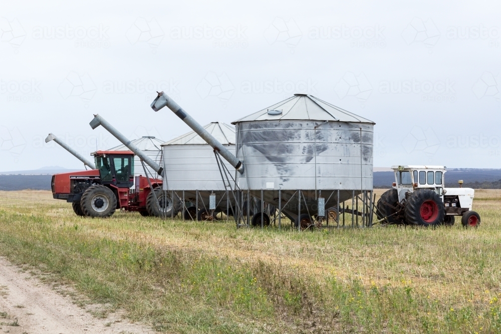 Image of Tractors and field bins in paddock - Austockphoto