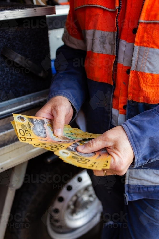 Image of Tradesman counting cash payment of fifties - Austockphoto