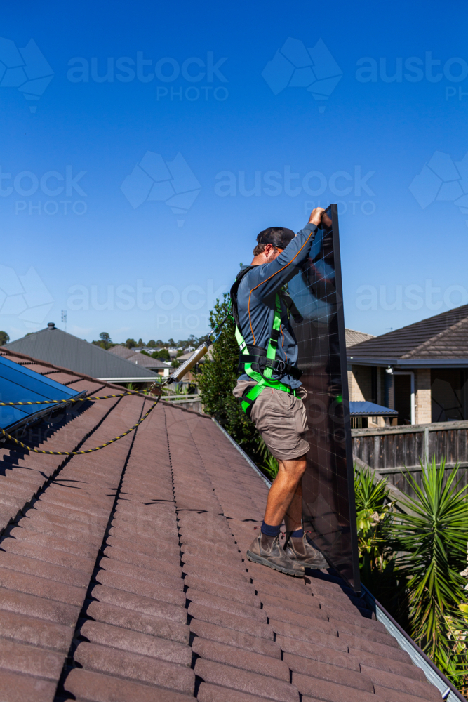 Image of Tradesman electrician lifting black bi-facial solar panels ...