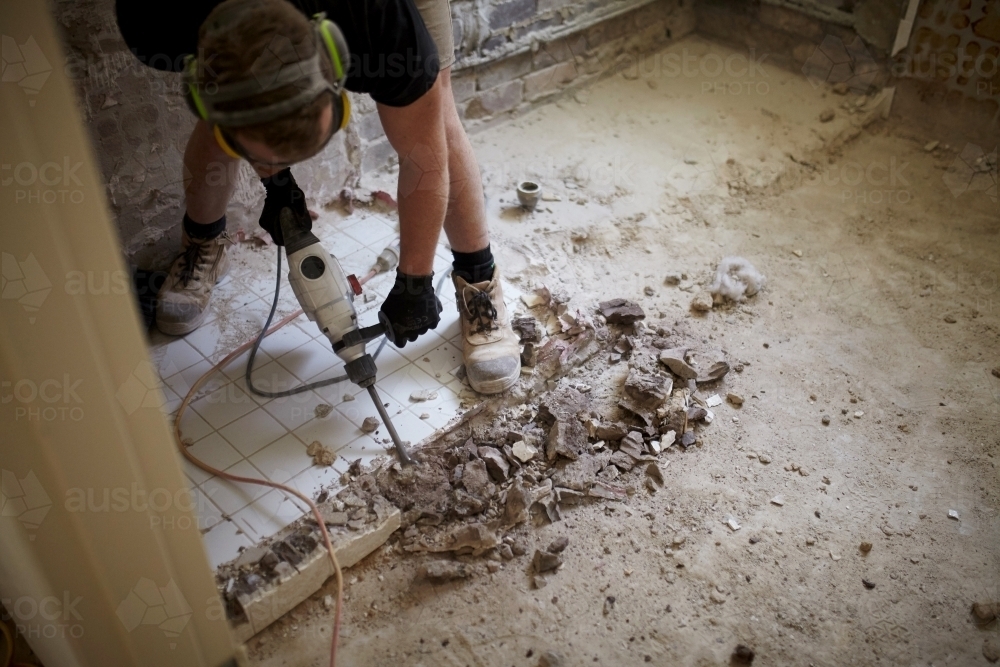 Image of Tradesman jackhammering tiles on a worksite - Austockphoto