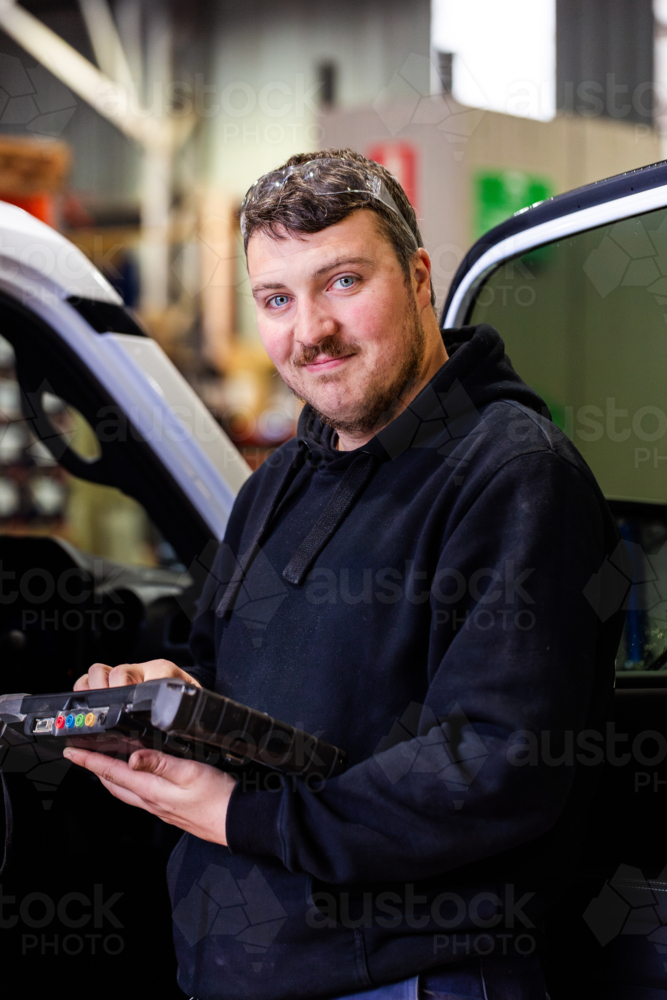 Image of tradesman mechanic with diagnostic device testing vehicle in ...