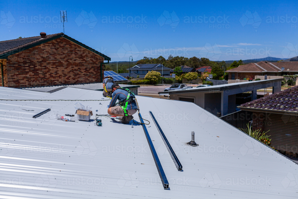 Image of Tradesmen in safety harness equipment installing rails for ...