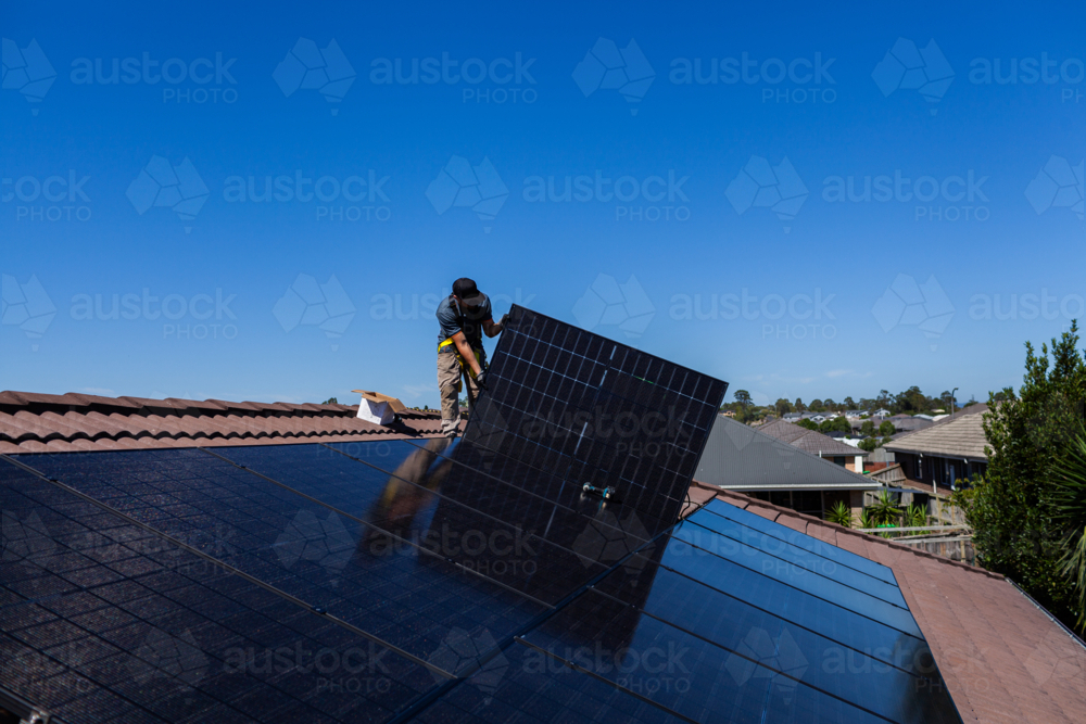 Image of Tradesperson installing bifacial solar panel on sunlit ...