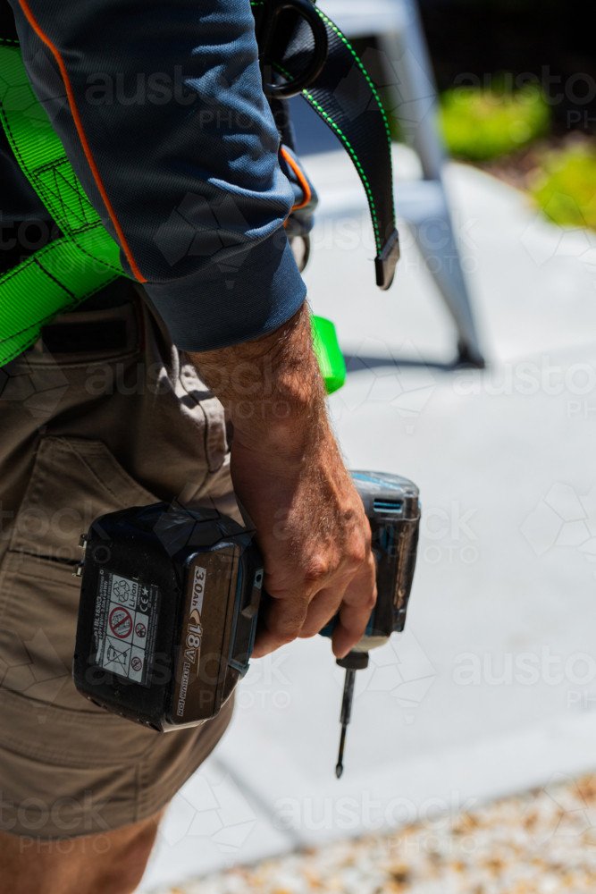 Image of tradesperson on worksite holding drill tool in hand during ...