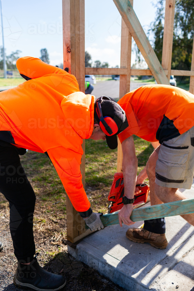 Image of Tradie apprentices using nail gun to secure temporary support ...