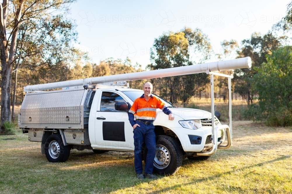 Image of Tradie man leaning on work vehicle in rural setting - Austockphoto