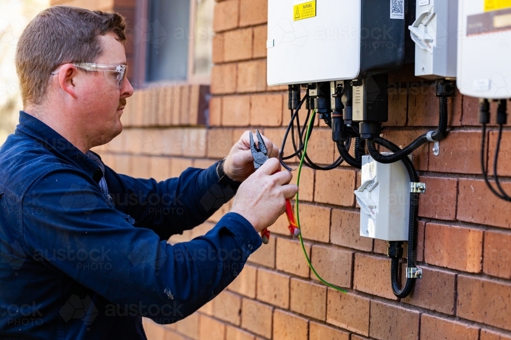Image of Tradie working as an electrician wiring a solar power control ...