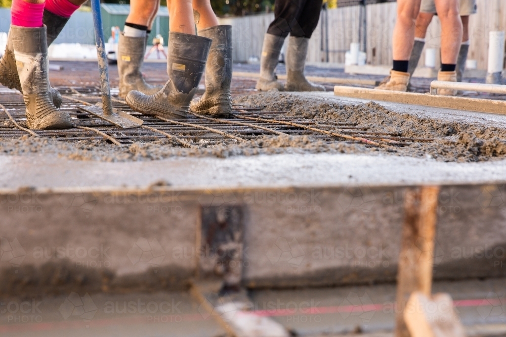Image of tradies in gumboots working on concrete slab pour - Austockphoto
