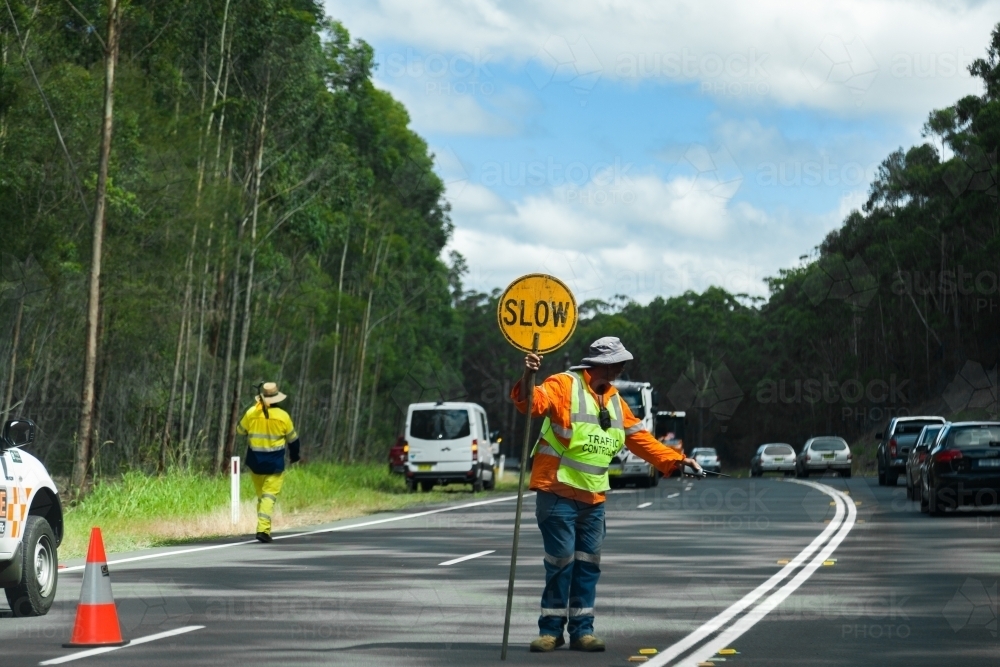 Image of Traffic controller with slow sign at roadworks - Austockphoto