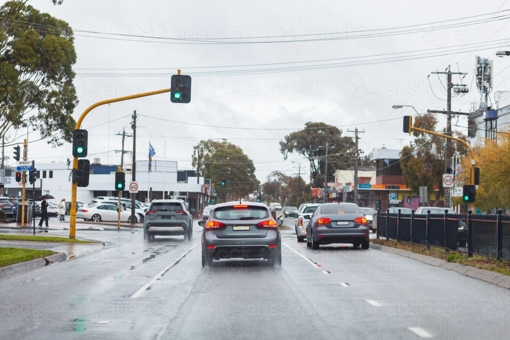 Image of Traffic lights at intersection with cars on rainy wet day with ...