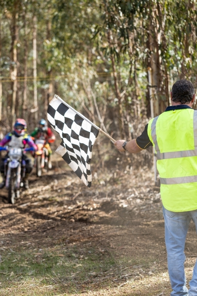 Image of Trail bikes approaching chequered flag at finish line of race ...