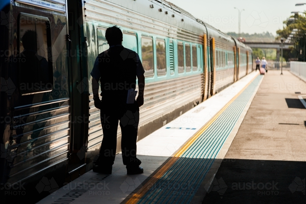 Image of Train guard silhouetted beside passenger train at train ...