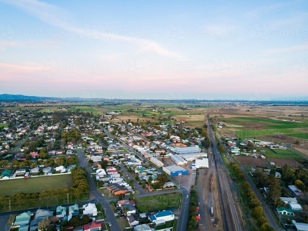 Image of Train track at edge of town with farm paddocks and dusk sky ...