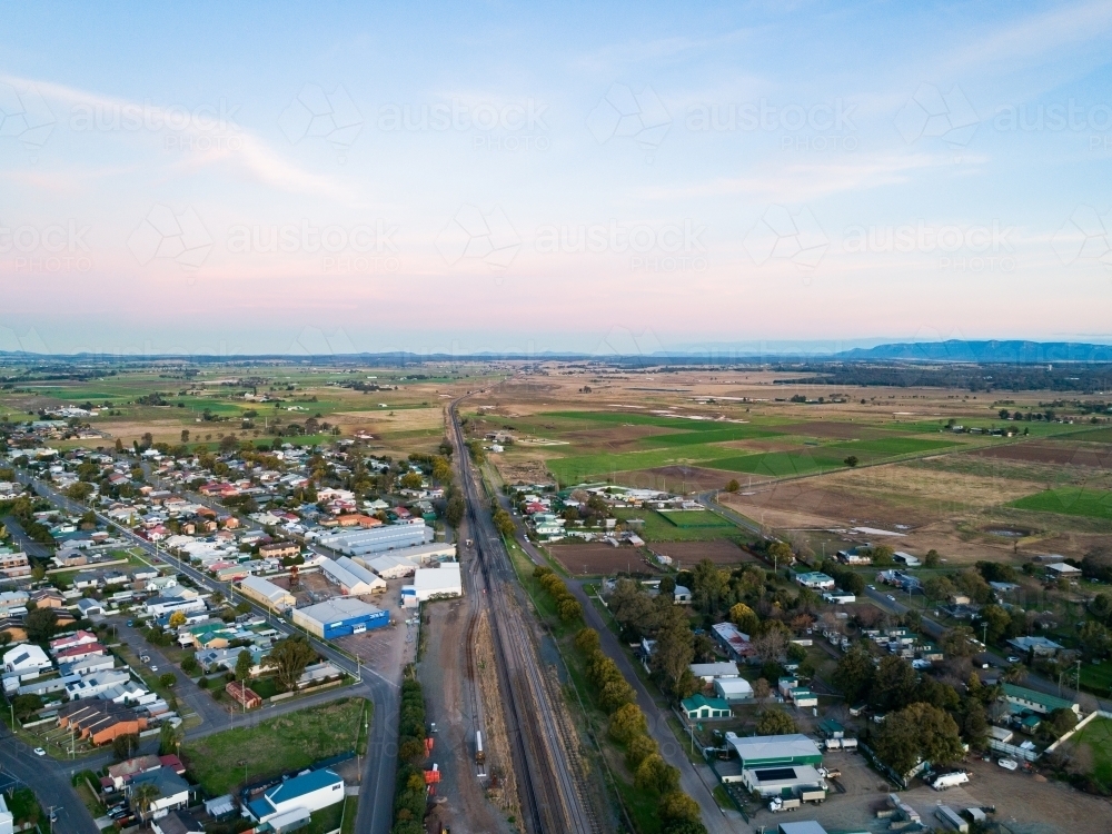 Image of Train track at edge of town with farm paddocks and dusk sky ...