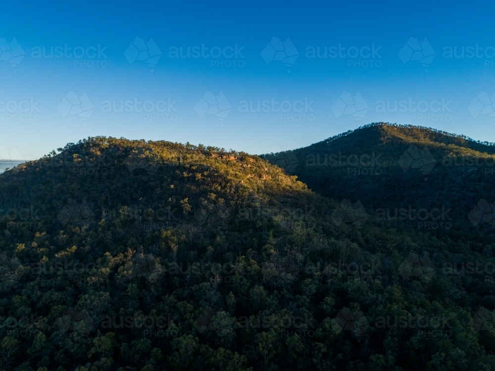 Image of Tree covered hills falling into shadow as the sun sets light ...