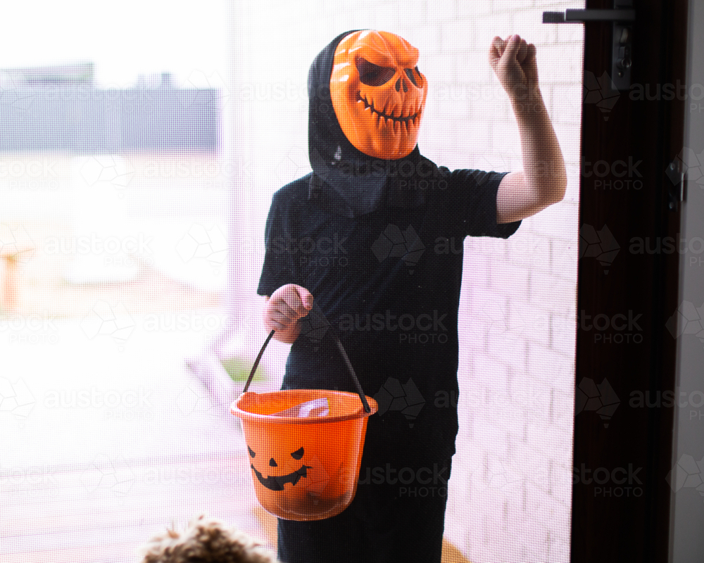 Image of trick or treater knocking on a door for halloween - Austockphoto
