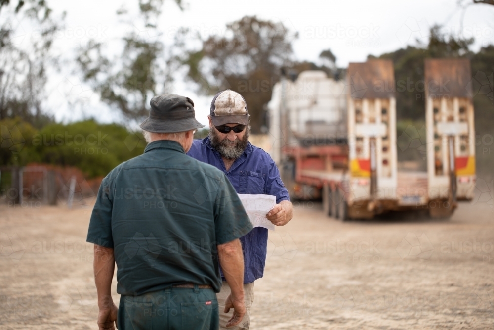 Image of truck driver and farmer discussing paperwork - Austockphoto