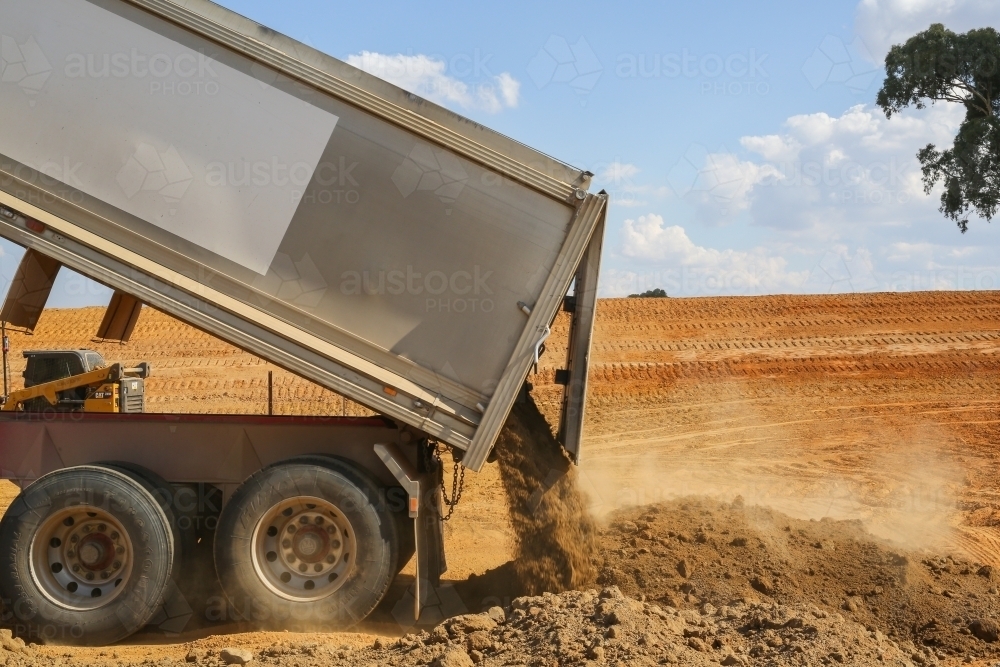 Image of truck tipping soil on a construction site - Austockphoto