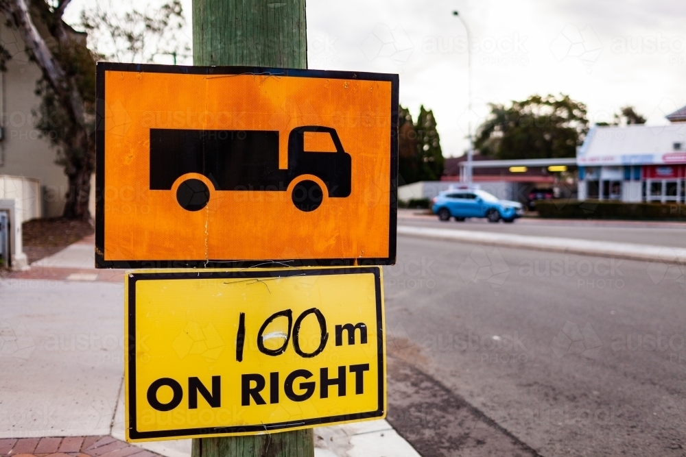 Image of Trucks turning 100m on right sign in town - Austockphoto