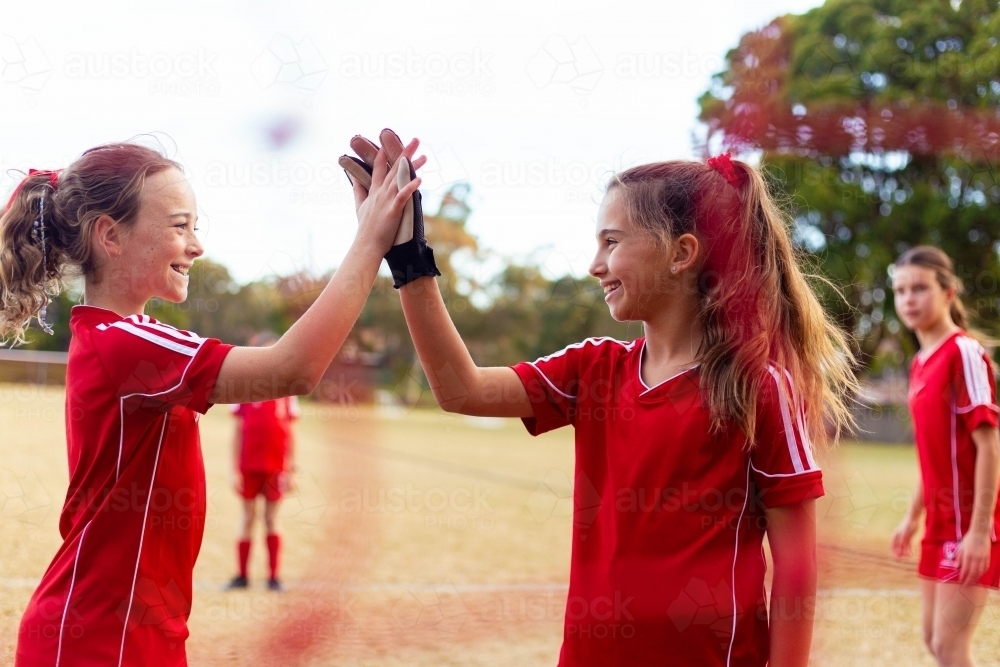 Image of Tween female soccer players high-five in front of the goal net ...