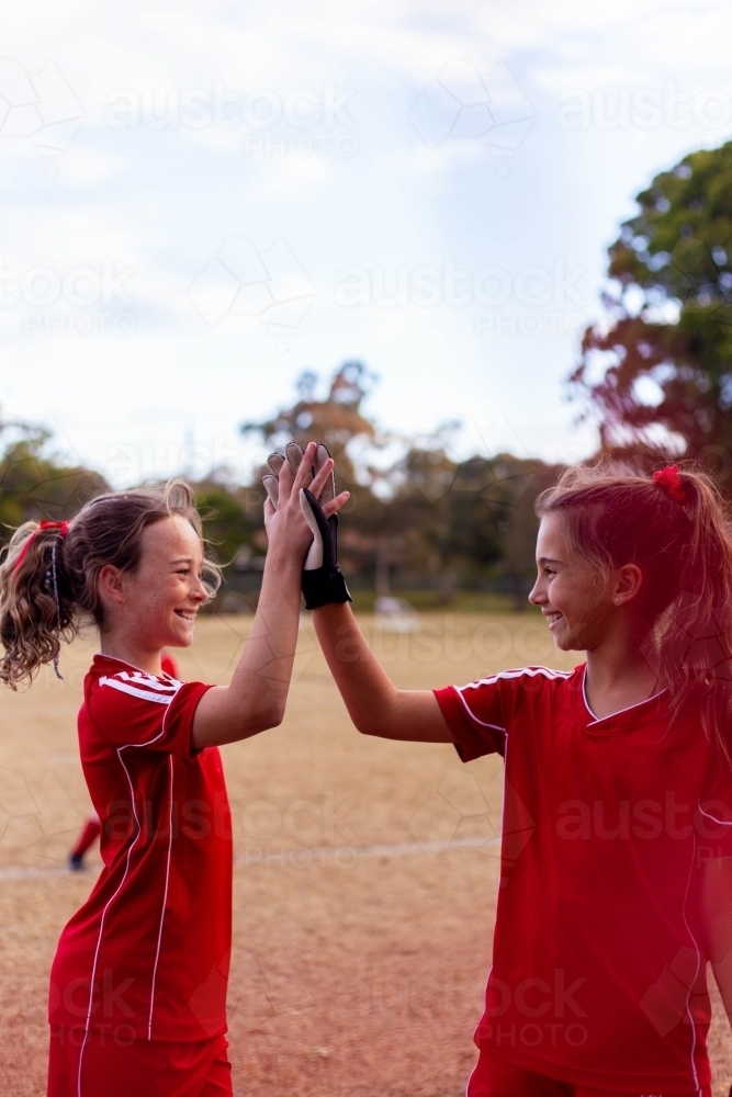 Image of Tween female soccer players high-five in front of the goal net ...