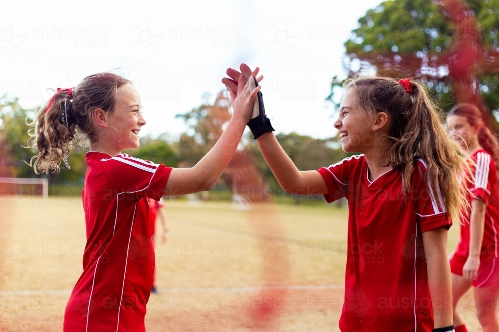 Image of Tween female soccer players high-five in front of the goal net ...
