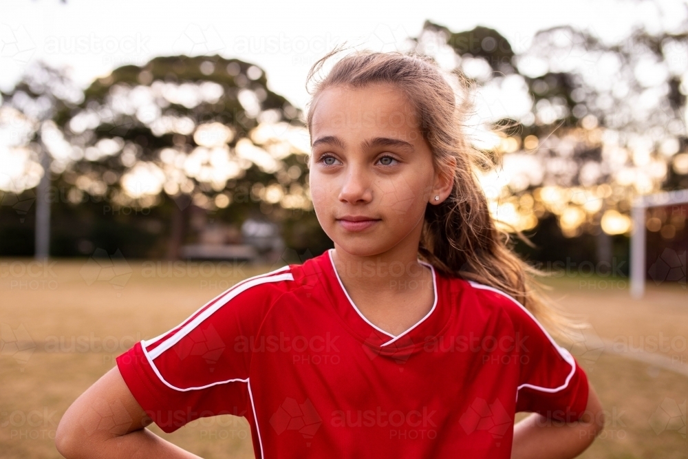 Image of Tween girl in a red sports uniform thinking and pondering ...