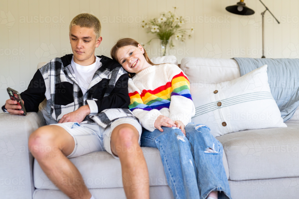 Image of Tween girl sitting beside teen brother on the couch holding ...