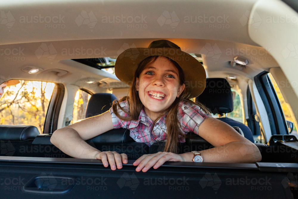 Image of Tween girl smiling looking over back seats of car during road ...
