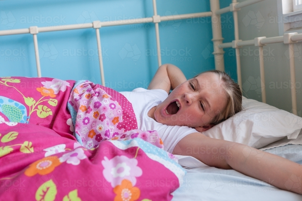 Image of Tween girl waking up with a big yawn - Austockphoto